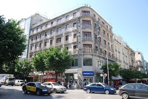 Um hotel com vários andares, varandas, um letreiro ProtonBank e um letreiro Coca-Cola.