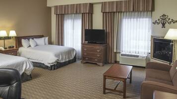 Quarto de hotel com duas camas, televisão, lareira e uma escrivaninha.