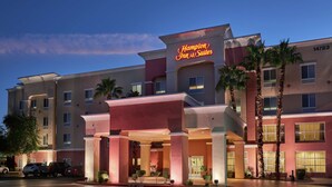 Um hotel com um letreiro de neon chamativo, vários andares e uma entrada bem iluminada.
