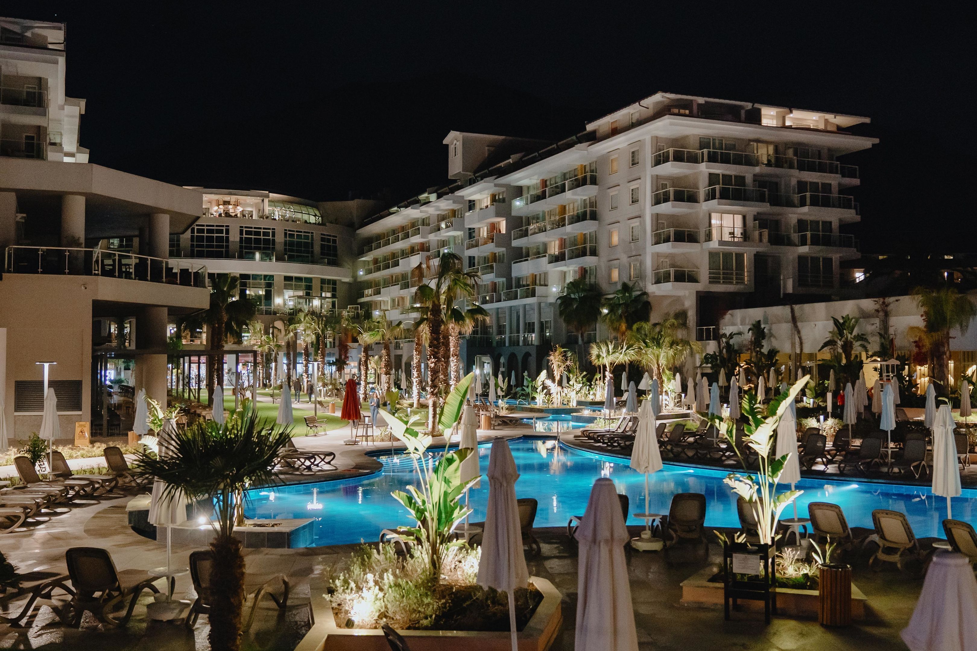 Uma área de piscina de hotel com espreguiçadeiras, guarda-sóis e uma piscina grande.