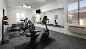 Uma academia com equipamentos de exercícios, um espelho grande e vista para o exterior.
