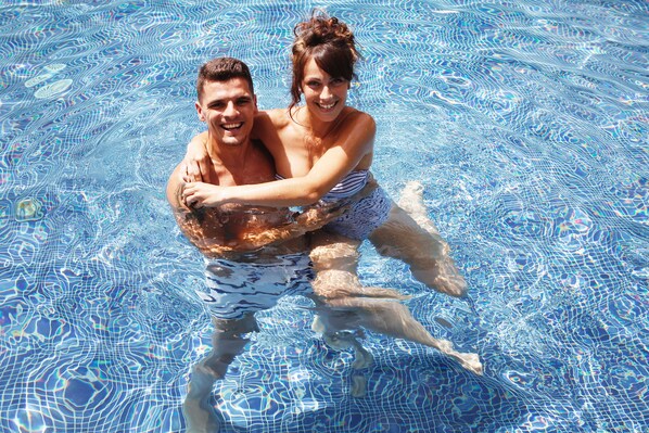 Um casal em uma piscina com água cristalina e ondulações visíveis.