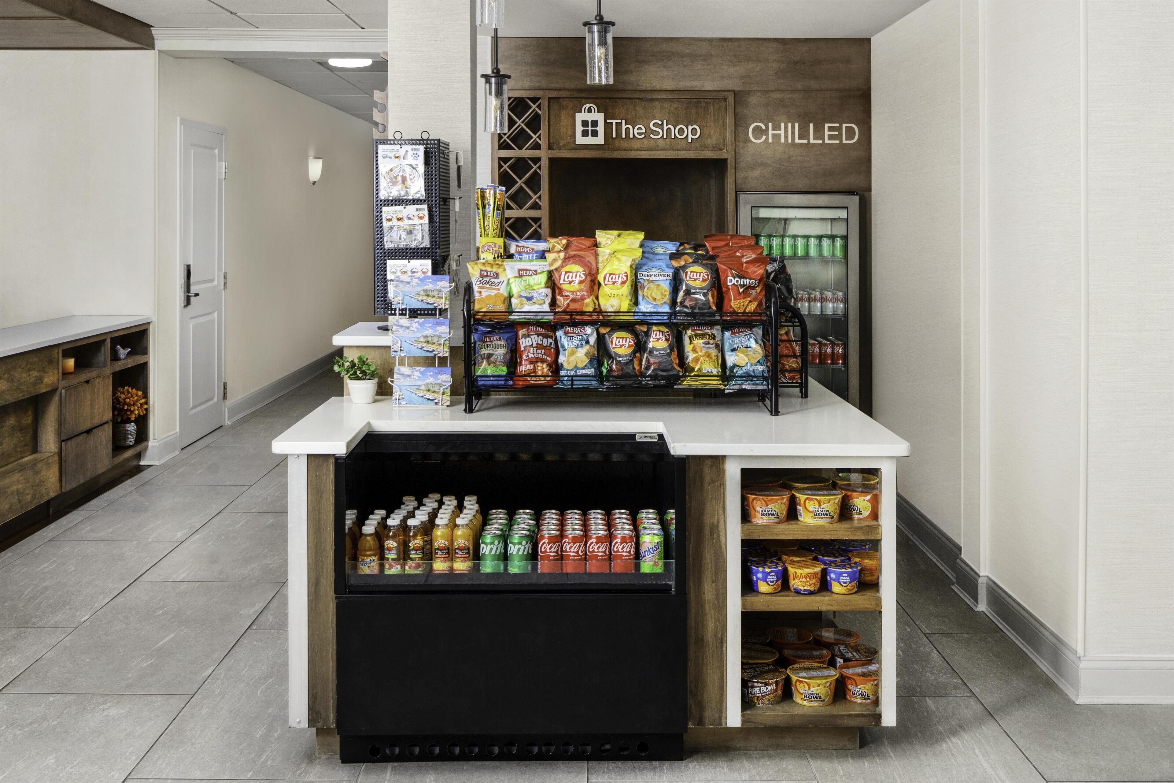 Quiosque de lanches e bebidas com diversas opções de salgadinhos e refrigerantes, incluindo Coca-Cola e Dr. Pepper.