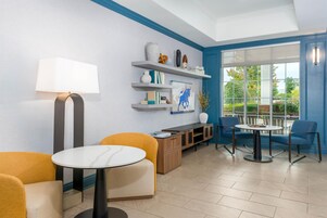 Uma área de estar moderna com assentos, uma mesa e uma estante com objetos decorativos.