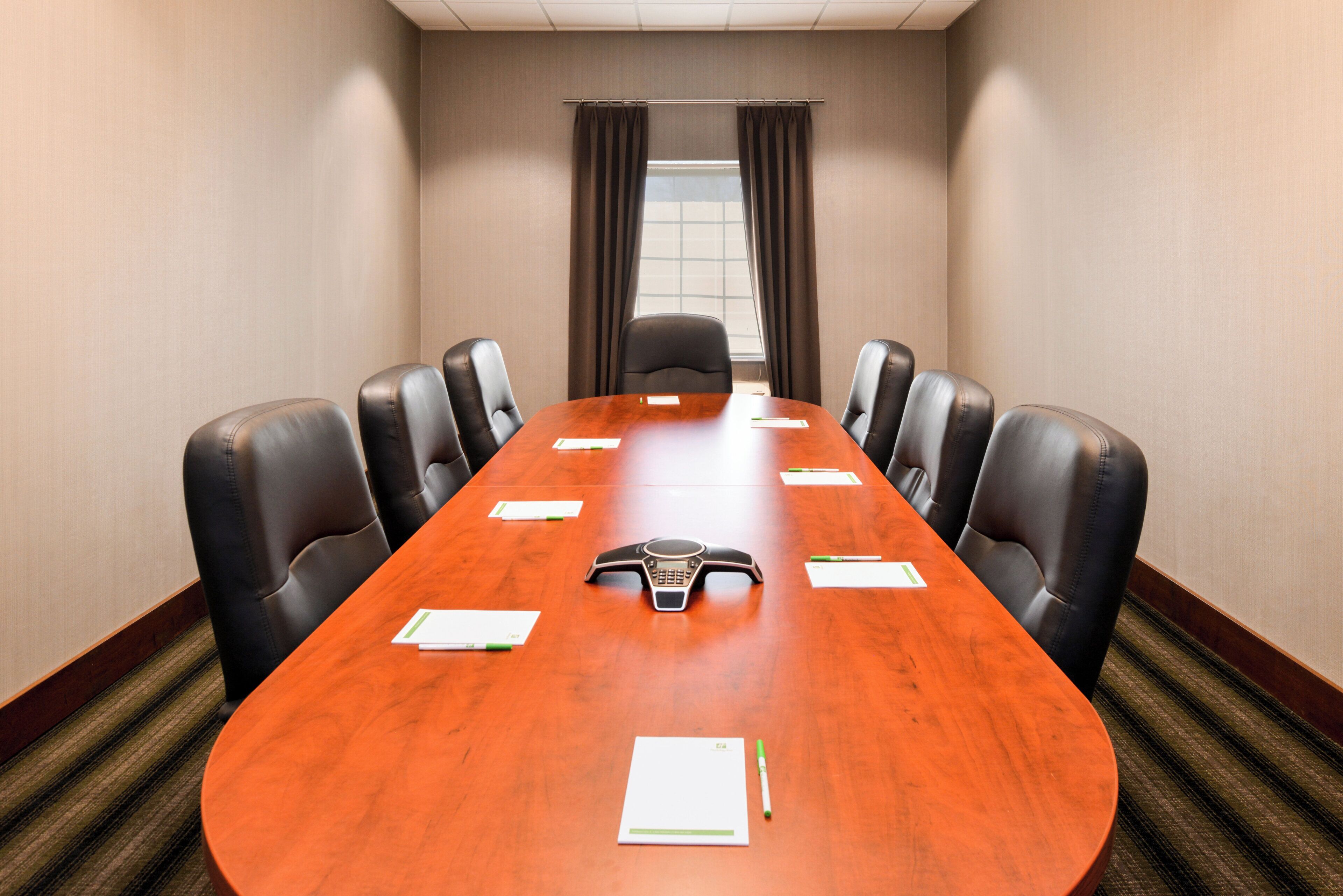 Sala de conferência com uma mesa comprida, seis cadeiras, um telefone e documentos.