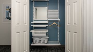 Um corredor com porta branca, parede azul e um armário de metal com cesta e cabide.