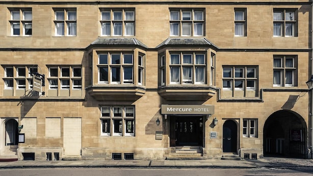 Um edifício histórico com várias janelas e uma entrada imponente com a inscrição "Mercure Hotel".