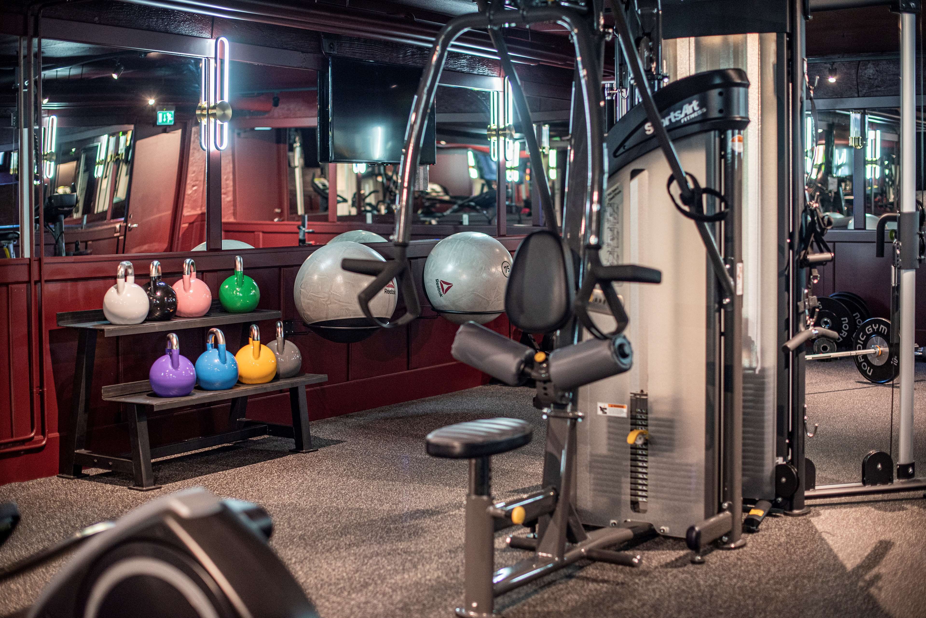 Uma academia com equipamentos de ginástica, um banco e anilhas.
