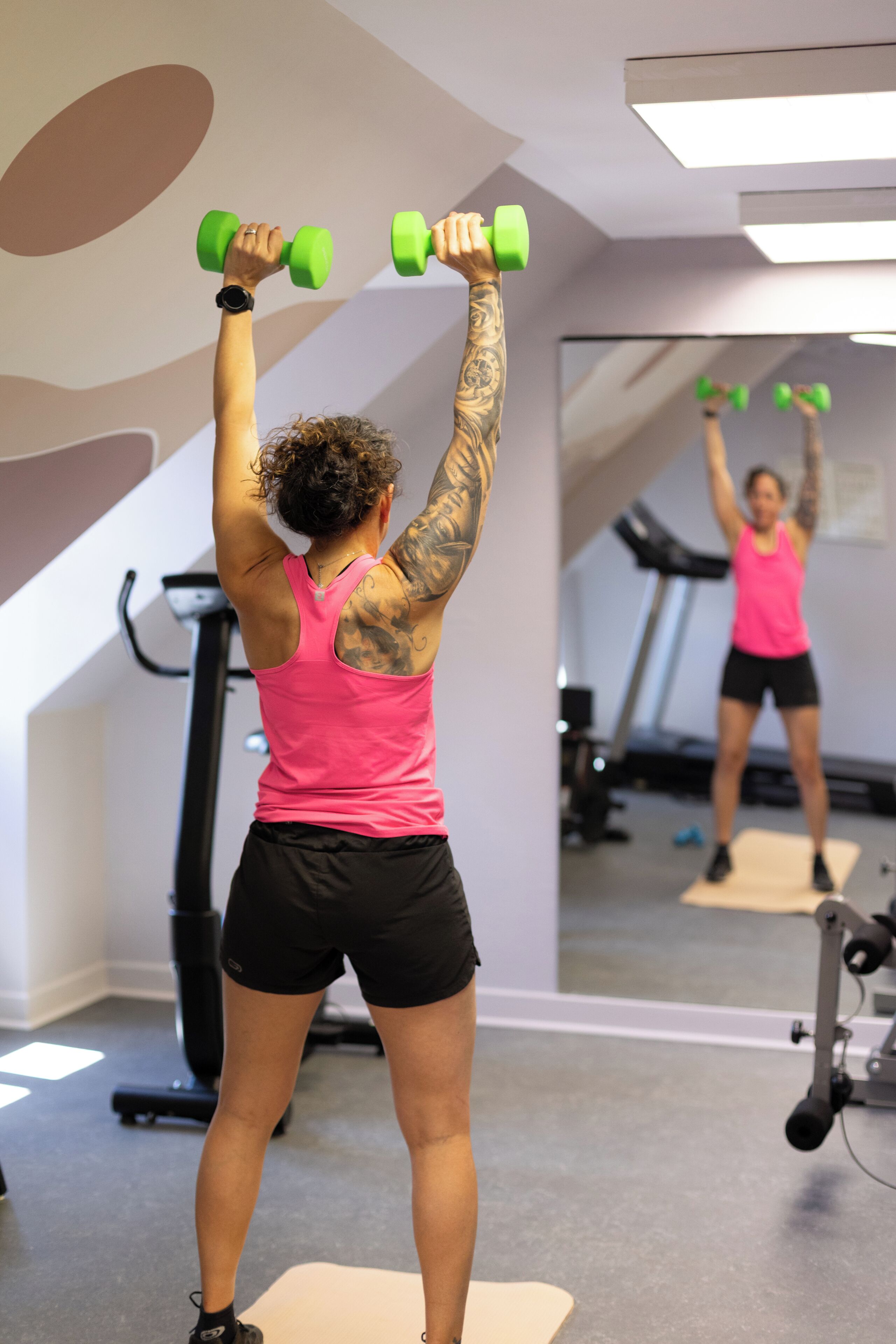 Academia com equipamentos de ginástica, esteira e uma pessoa levantando halteres.
