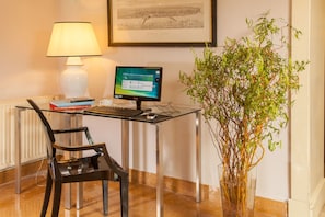 Uma mesa de escritório moderna com um computador, uma cadeira, uma luminária e um vaso de planta.