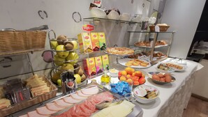 Buffet com diversas opções de comida, incluindo frutas, doces e embutidos.