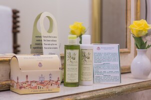 Exibição de comodidades do hotel, incluindo um folheto, loção corporal e sabonete líquido para cabelo e corpo.