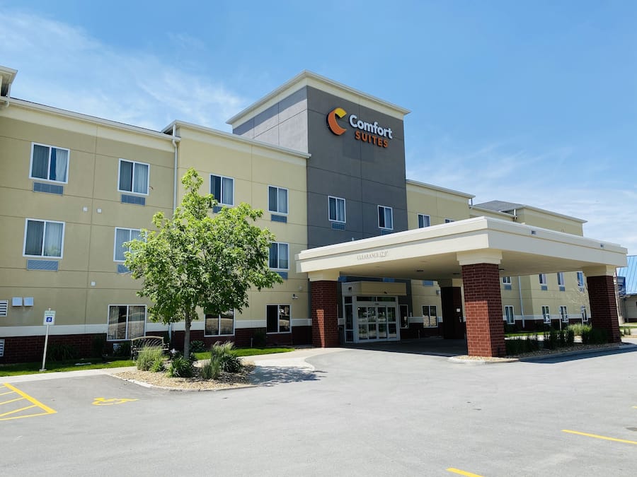 Hotel Comfort Suites com entrada acessível, estacionamento e sinalização de vagas para deficientes.