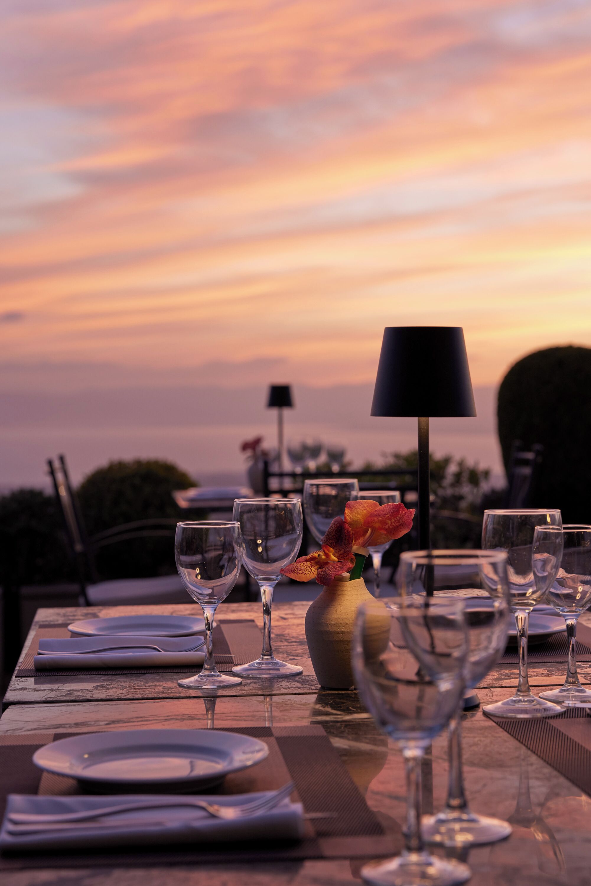 Mesa posta para refeição com vista para o pôr do sol.