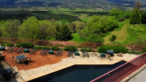 Área de piscina no terraço com vista para o campo.