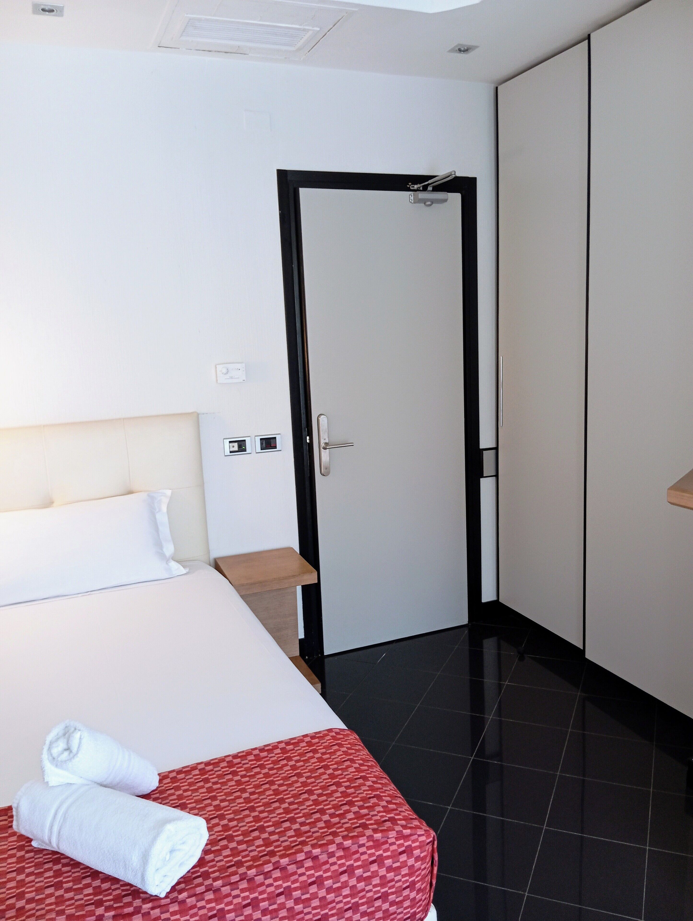 Quarto de hotel com cama, guarda-roupa e porta.