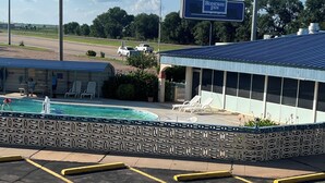 Um motel com piscina, varanda coberta e estacionamento.