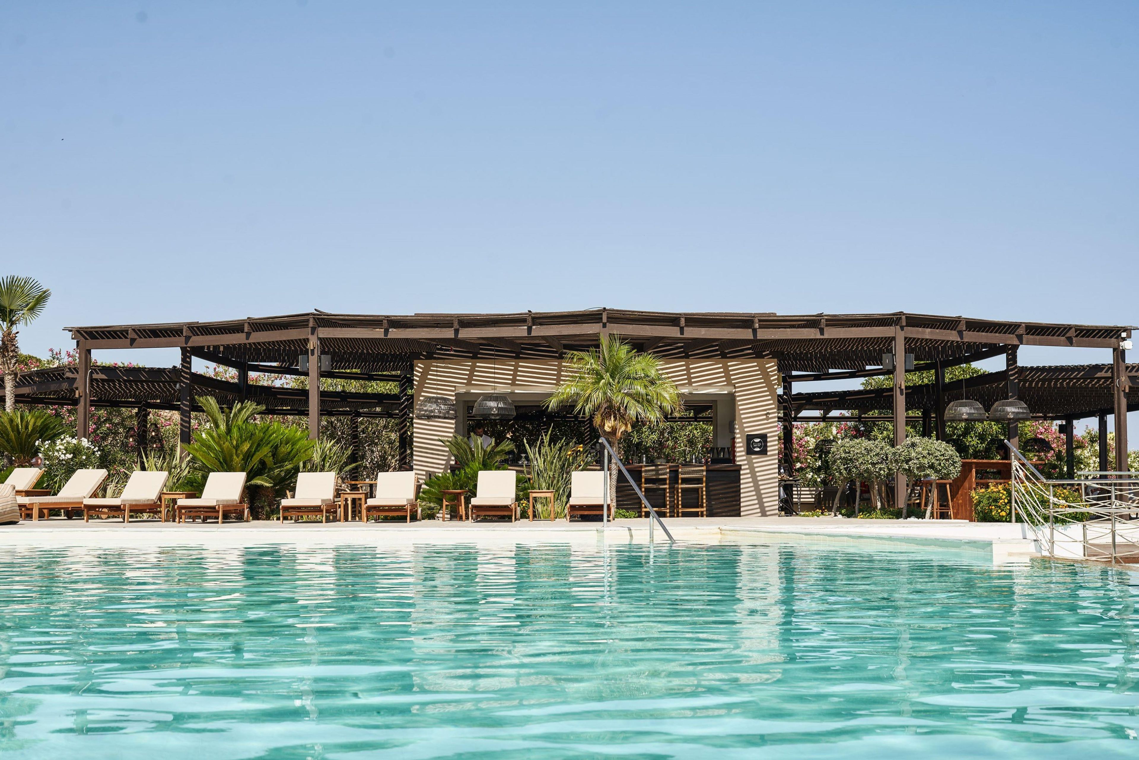 Uma área de piscina com espreguiçadeiras e um espaço de estar coberto.