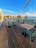 Um terraço com mesas e cadeiras, com vista para um corpo d'água.