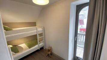 Quarto com beliches, uma pequena estatueta de veado de madeira e vista para uma varanda com guarda-corpo.