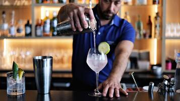 Um bartender servindo uma bebida num copo, com uma fatia de limão.