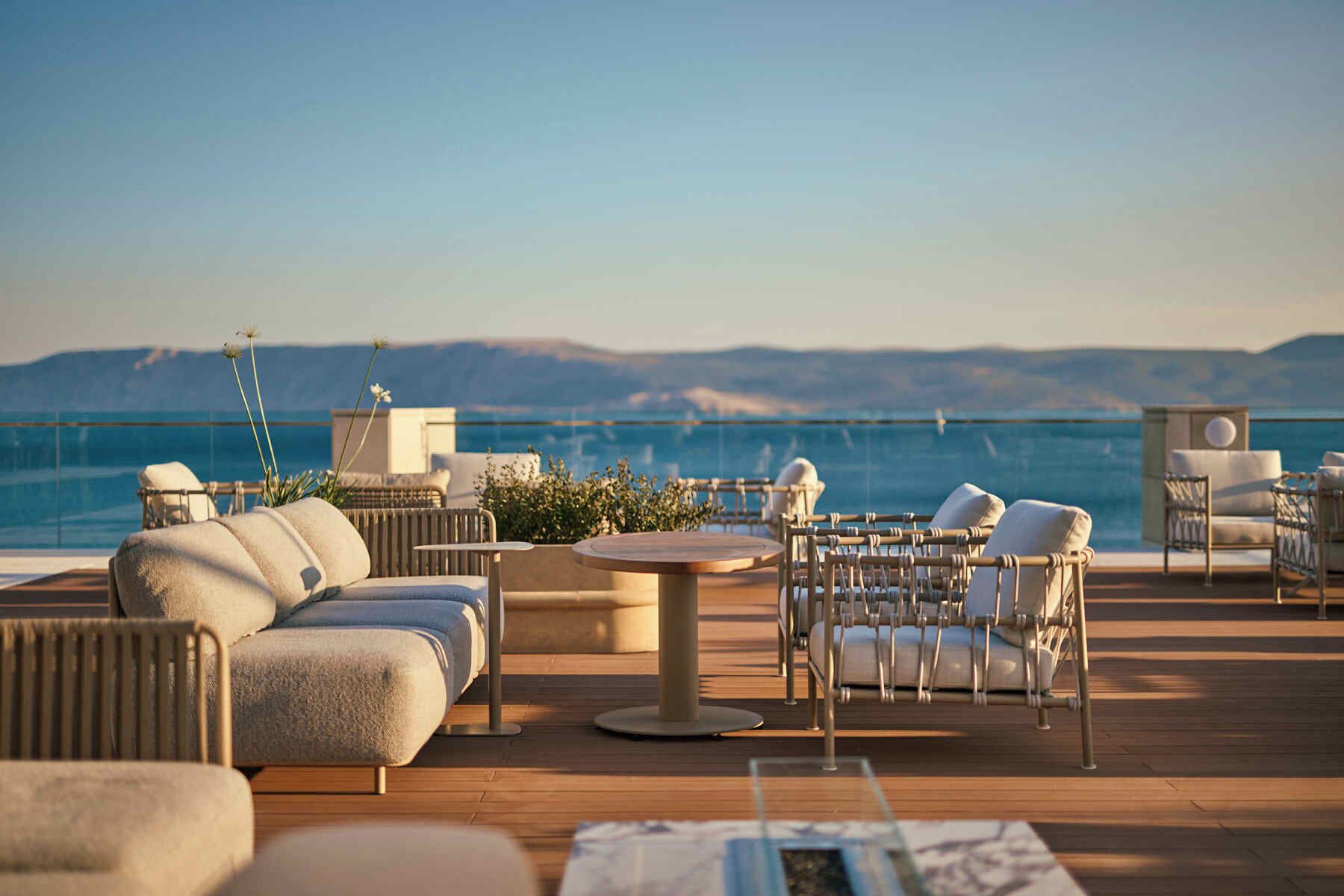Um terraço com assentos e vista para o mar.