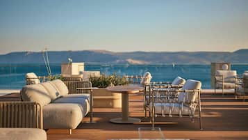 Um terraço com assentos e vista para o mar.