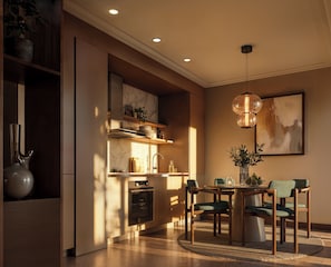 Uma cozinha moderna com eletrodomésticos embutidos, um espaço de jantar com mesa e cadeiras redondas, e uma luminária pendente.