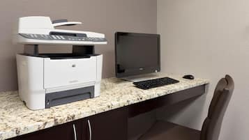 Um espaço de trabalho com um computador de mesa, uma impressora e uma cadeira.