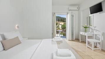 Quarto de hotel com cama, escrivaninha, cadeira, televisão e vista para o exterior.