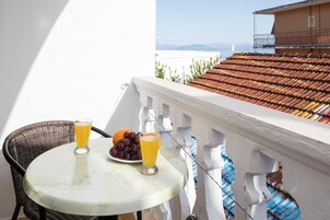 Varanda com mesa posta para dois, exibindo um copo de suco de laranja e um prato de uvas.