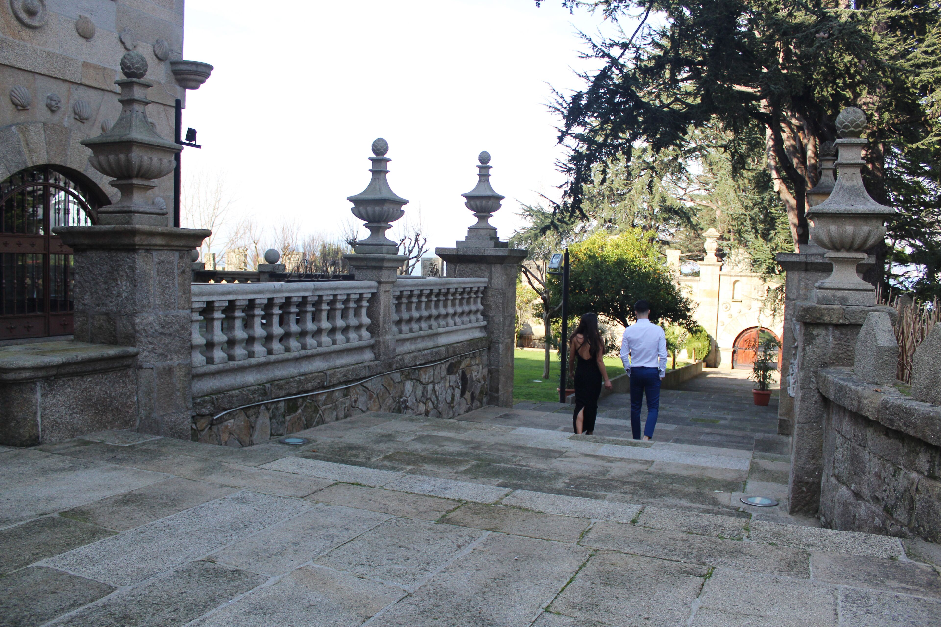 Uma escadaria de pedra que leva a um edifício com balaústres ornamentados e portão.