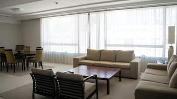 Uma sala de estar moderna com sofá, poltronas, mesa de centro e um espaço de jantar com cadeiras e mesa.