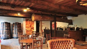 Decoração rústica com móveis de madeira, espaço de bar e grandes barris.