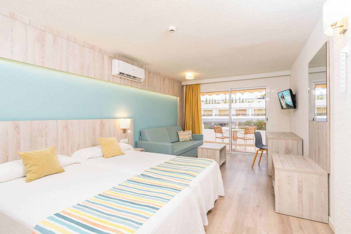 Quarto de hotel com uma cama grande, um sofá, uma mesa e uma televisão.