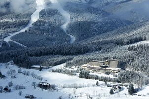 Um edifício grande, com vários andares, rodeado por colinas arborizadas cobertas de neve.