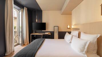 Quarto de hotel moderno com cama grande, escrivaninha, televisão de tela plana e varanda com cortinas.