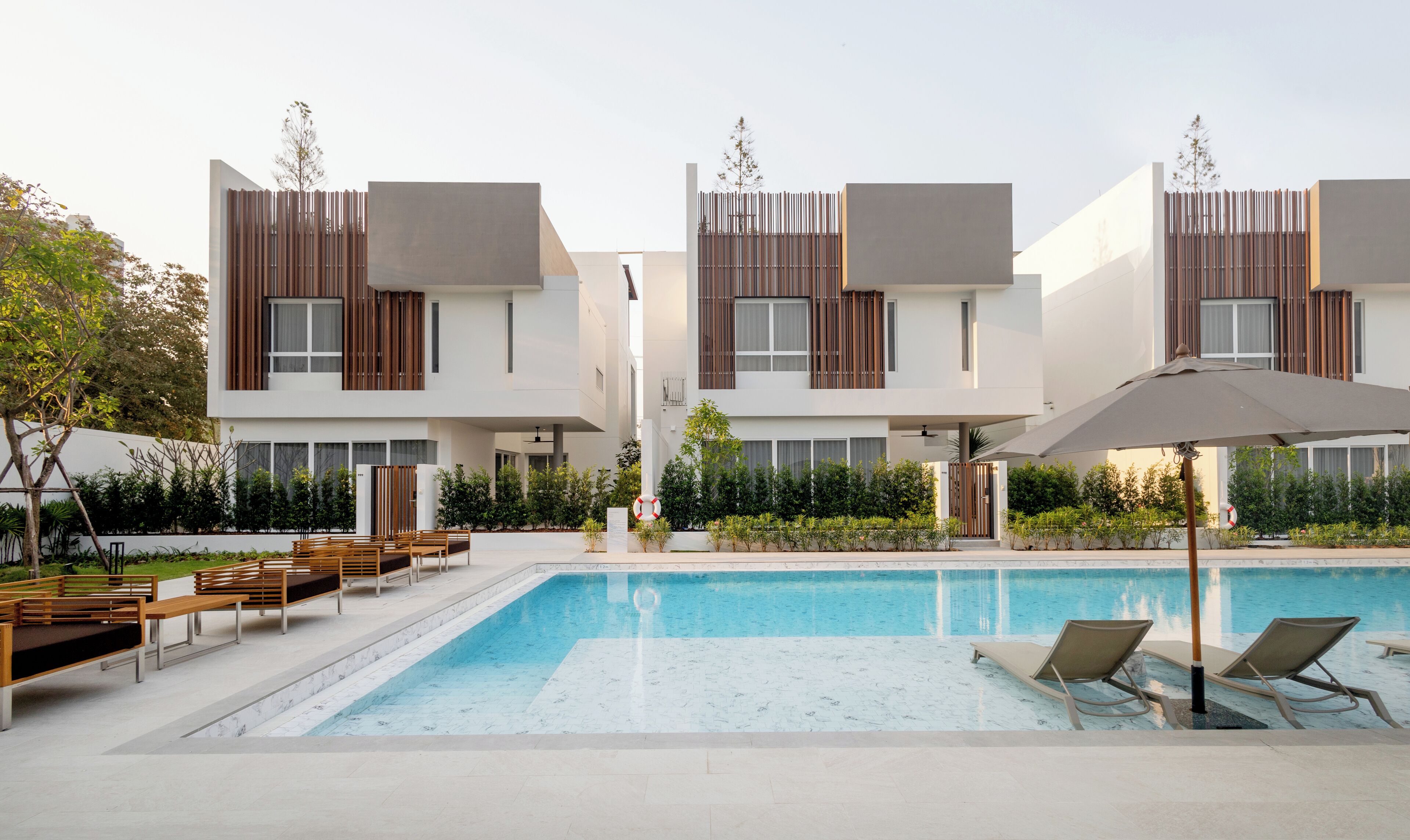 Um hotel moderno com piscina, área de estar ao ar livre e um jardim bem cuidado.