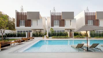 Um hotel moderno com piscina, área de estar ao ar livre e um jardim bem cuidado.