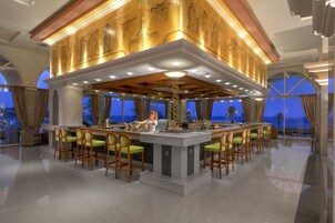 Uma área de bar com ilha central, vários bancos e vista para o exterior.