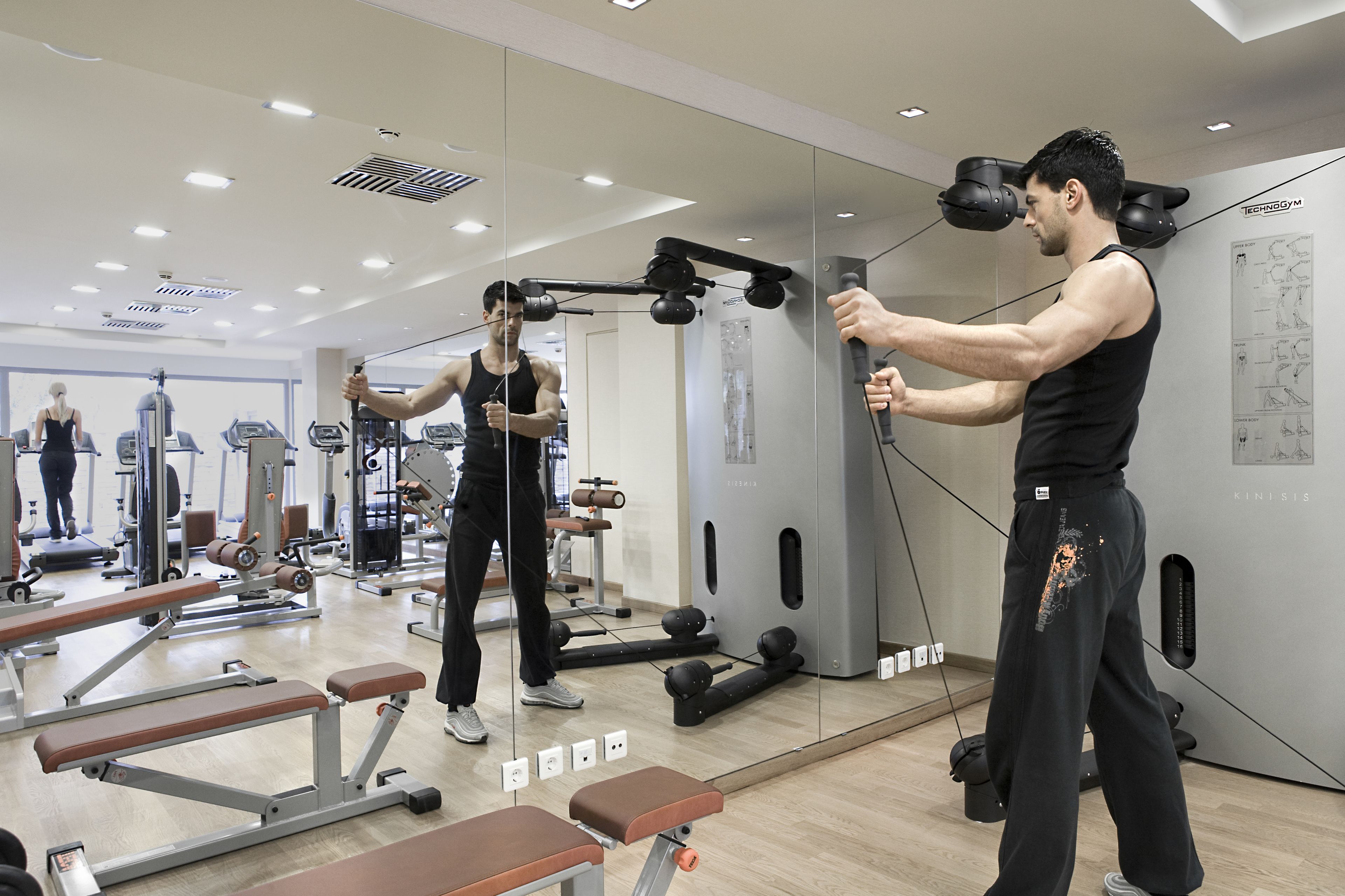 Uma academia com diversos equipamentos de exercício, incluindo bancos e aparelhos de musculação.