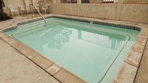 Piscina retangular com borda azulejada, rodeada por um deck de concreto.