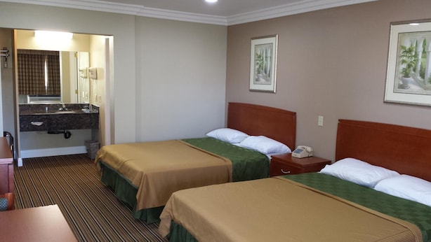 Quarto de hotel com duas camas, banheiro com pia e espelho.