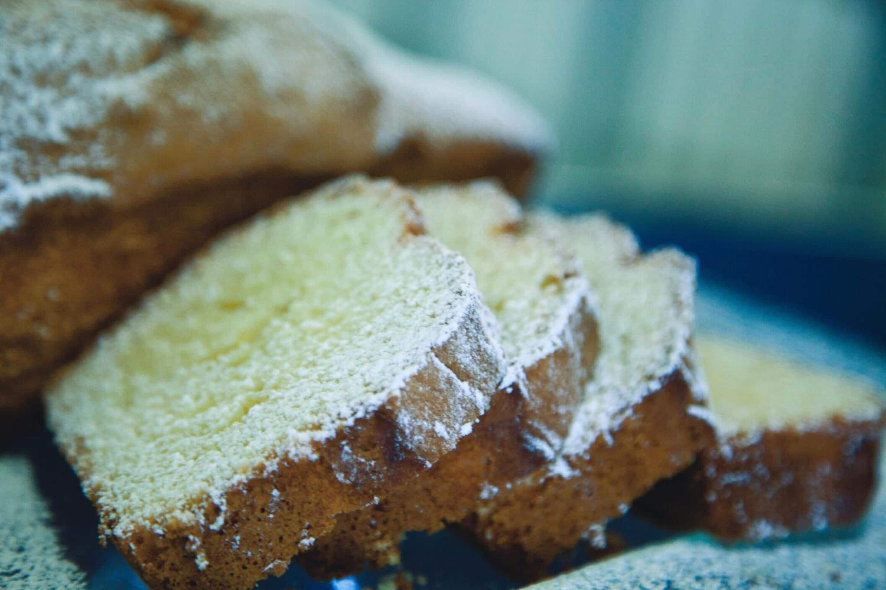 Fatias de bolo com açúcar de confeiteiro sobre um prato azul.