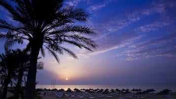 Na praia, praia de areia branca, espreguiçadeiras, guarda-sóis de praia
