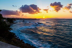 Vista de pôr do sol na costa com ondas quebrando na praia.