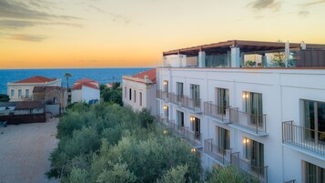 Um hotel à beira-mar com várias varandas, vista para o mar e uma mistura de arquitetura tradicional e moderna.
