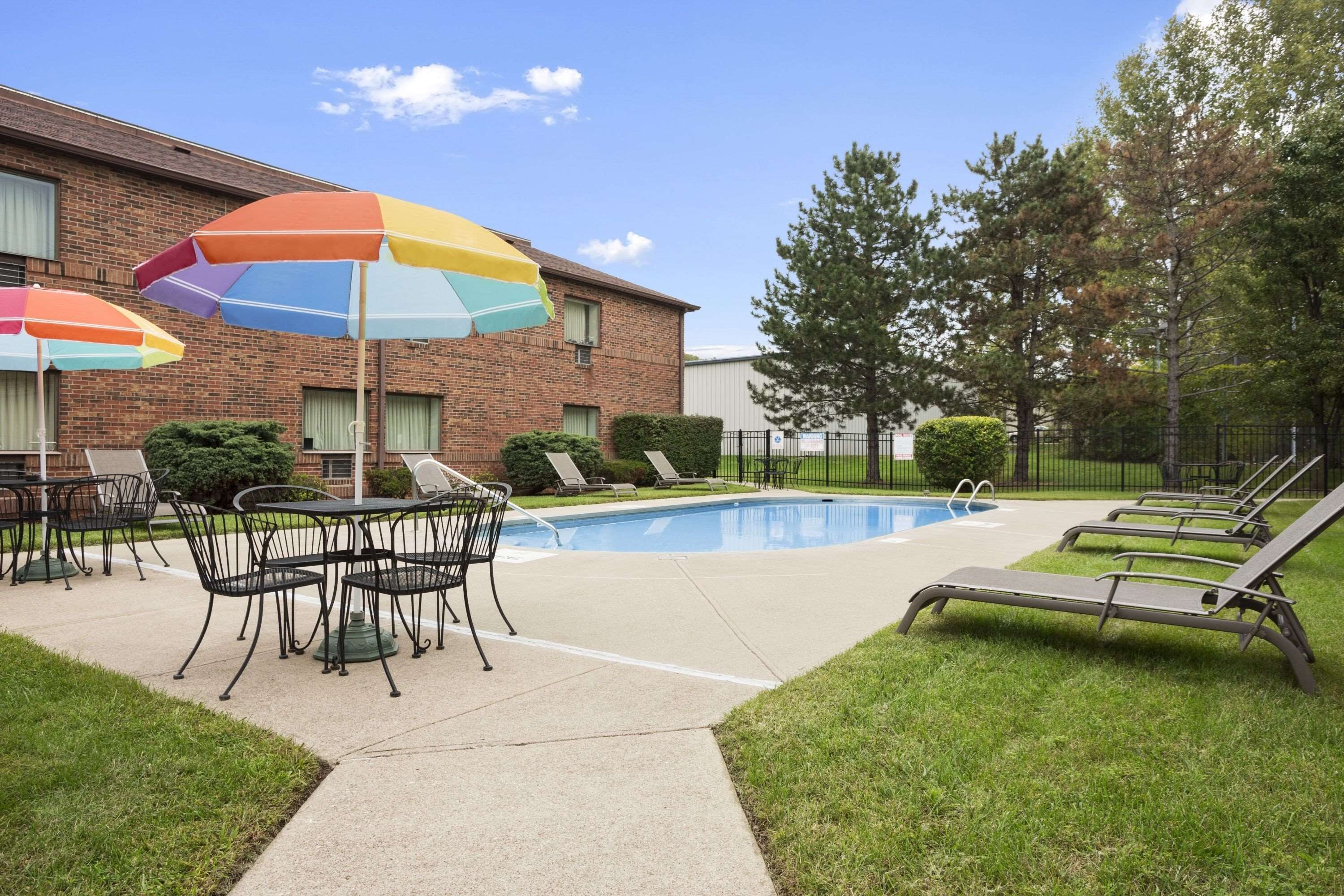 Área de piscina com espreguiçadeiras e mesa com guarda-sóis.