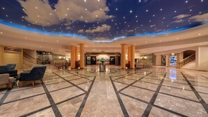 Um hall amplo com teto estrelado, piso de mármore e área de estar central.