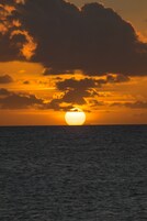 Um pôr do sol sobre o oceano com nuvens no céu.